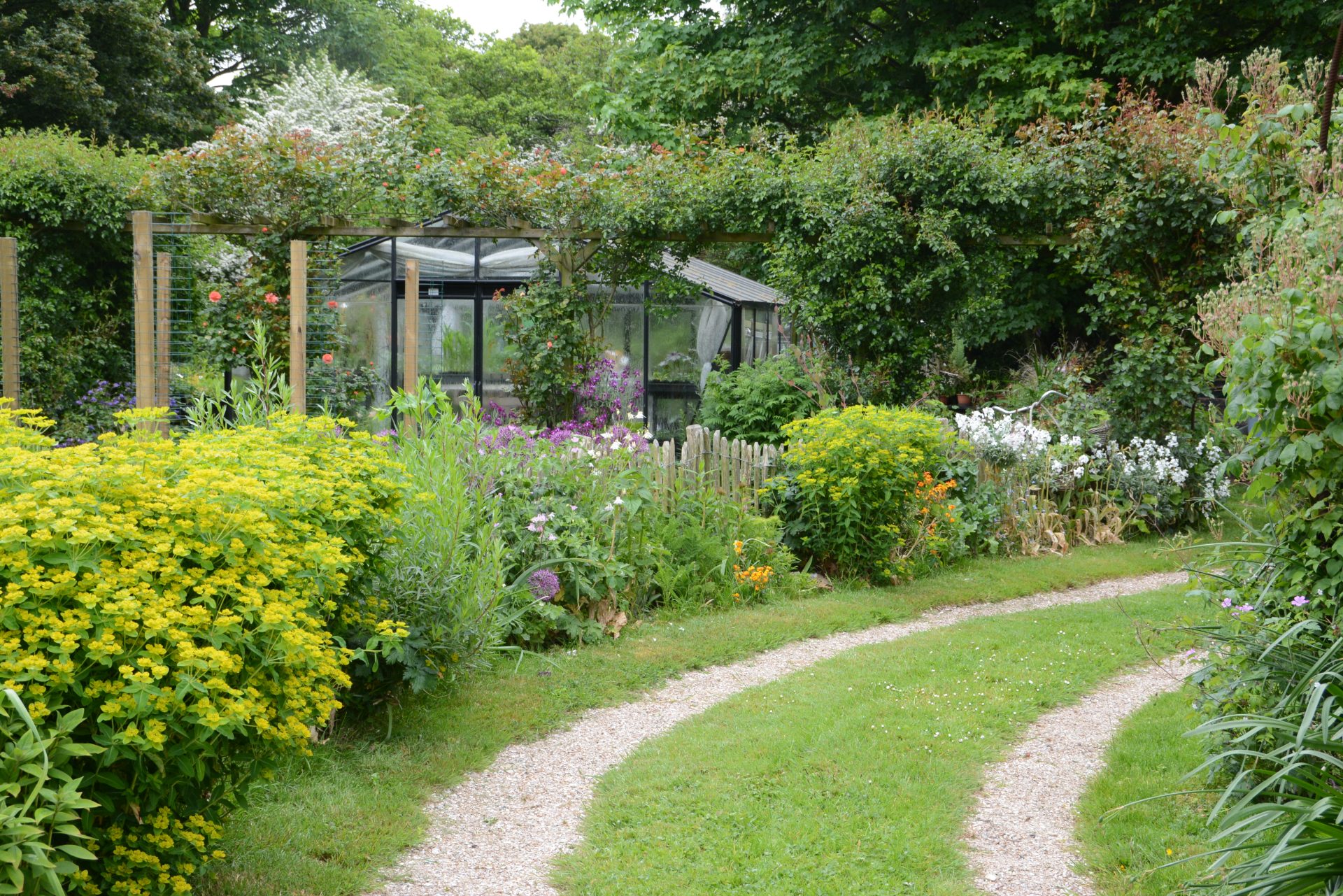 Karrenspoor met rozenpergola en kas : Nederlandse Tuinenstichting (NTs)